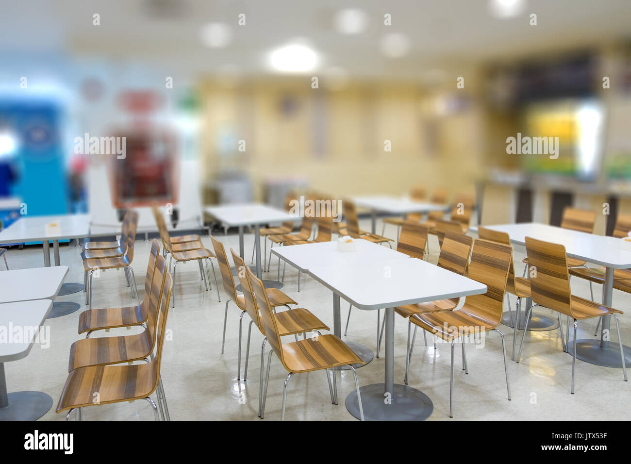 Blur of white table and wooden table on food court in shopping mall ...