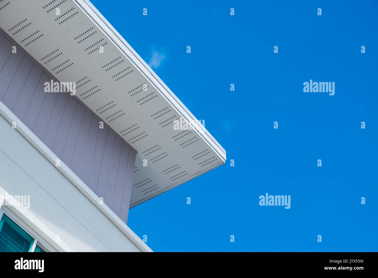 White eaves with ceiling and roof of modern house against blue sky ...