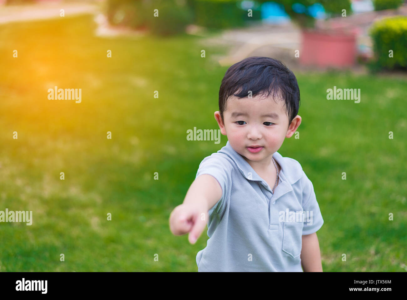 Little Asian kid at the playground under the sunlight in summer ...