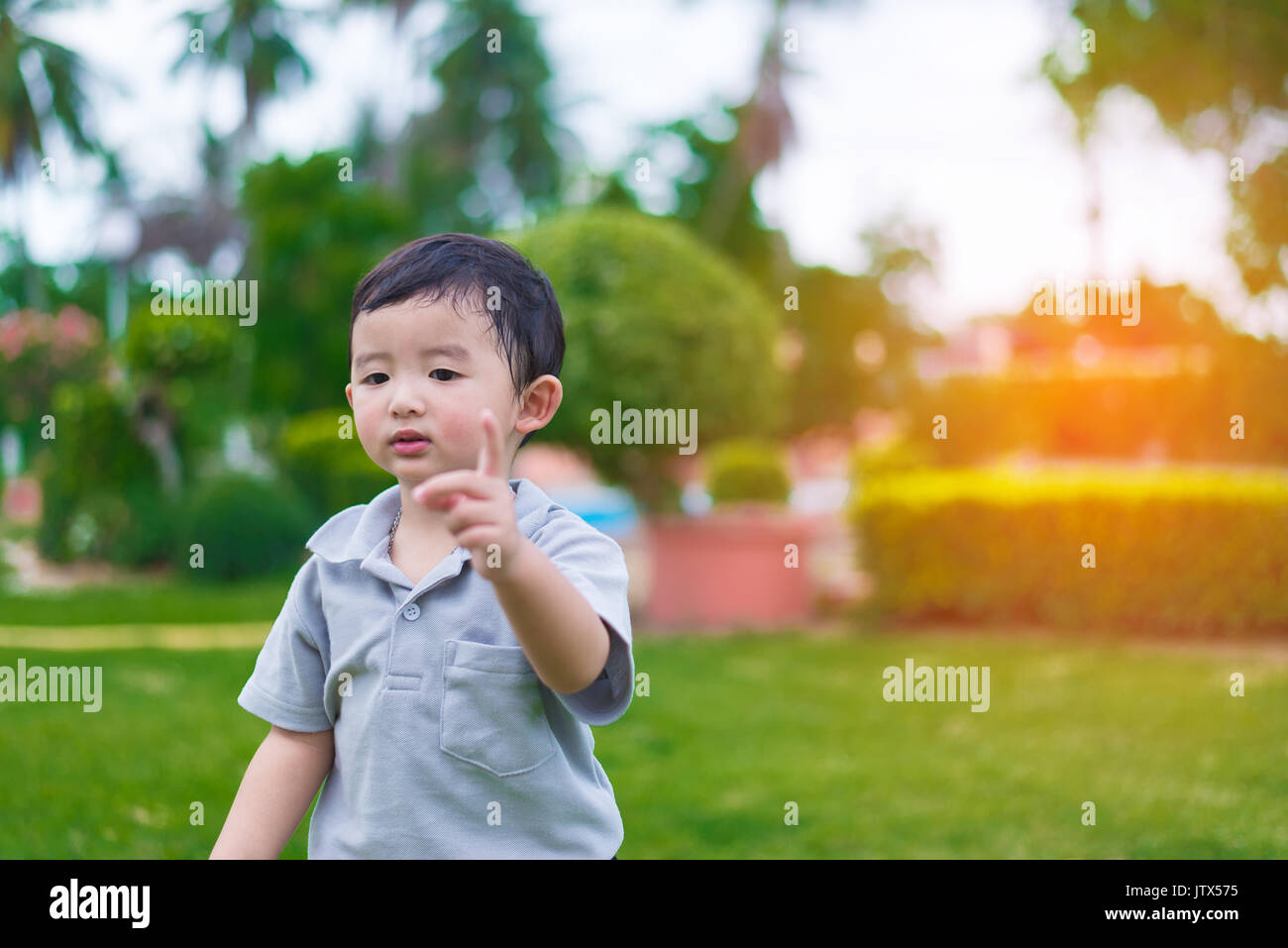 Little Asian kid at the playground under the sunlight in summer ...