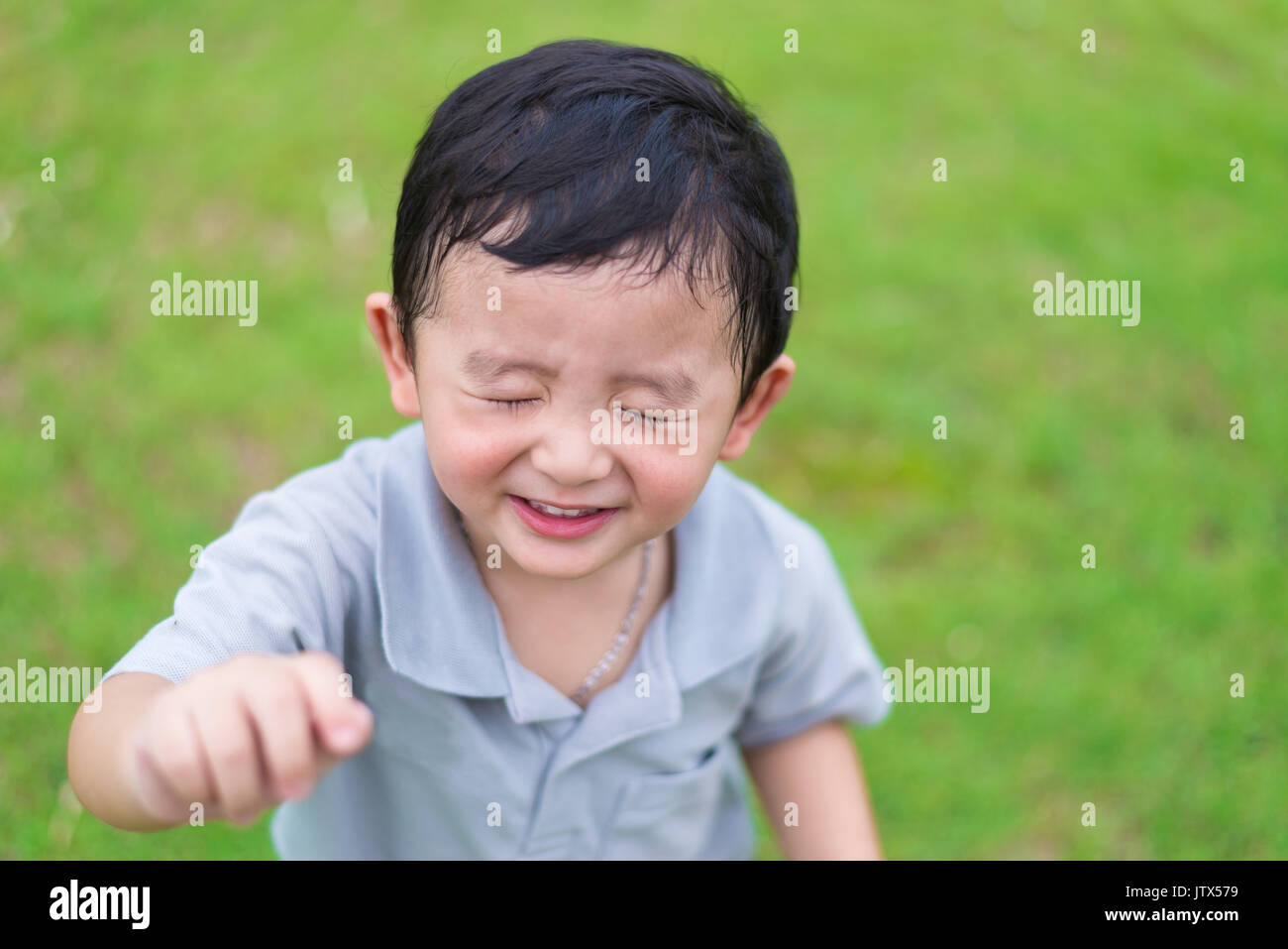Little Asian kid at the playground under the sunlight in summer ...