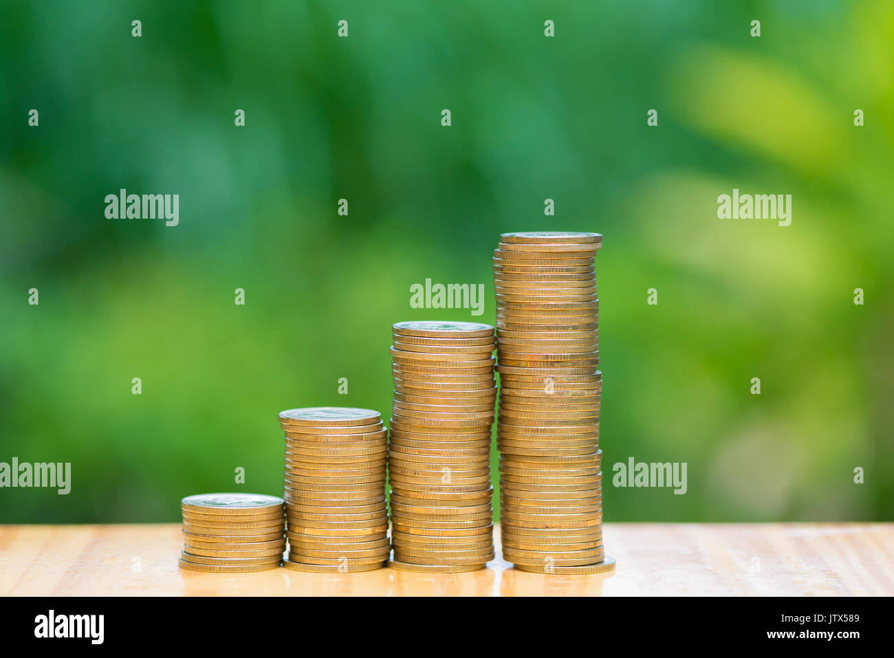 Growing coins stacks on wood with green tree bokeh background ...
