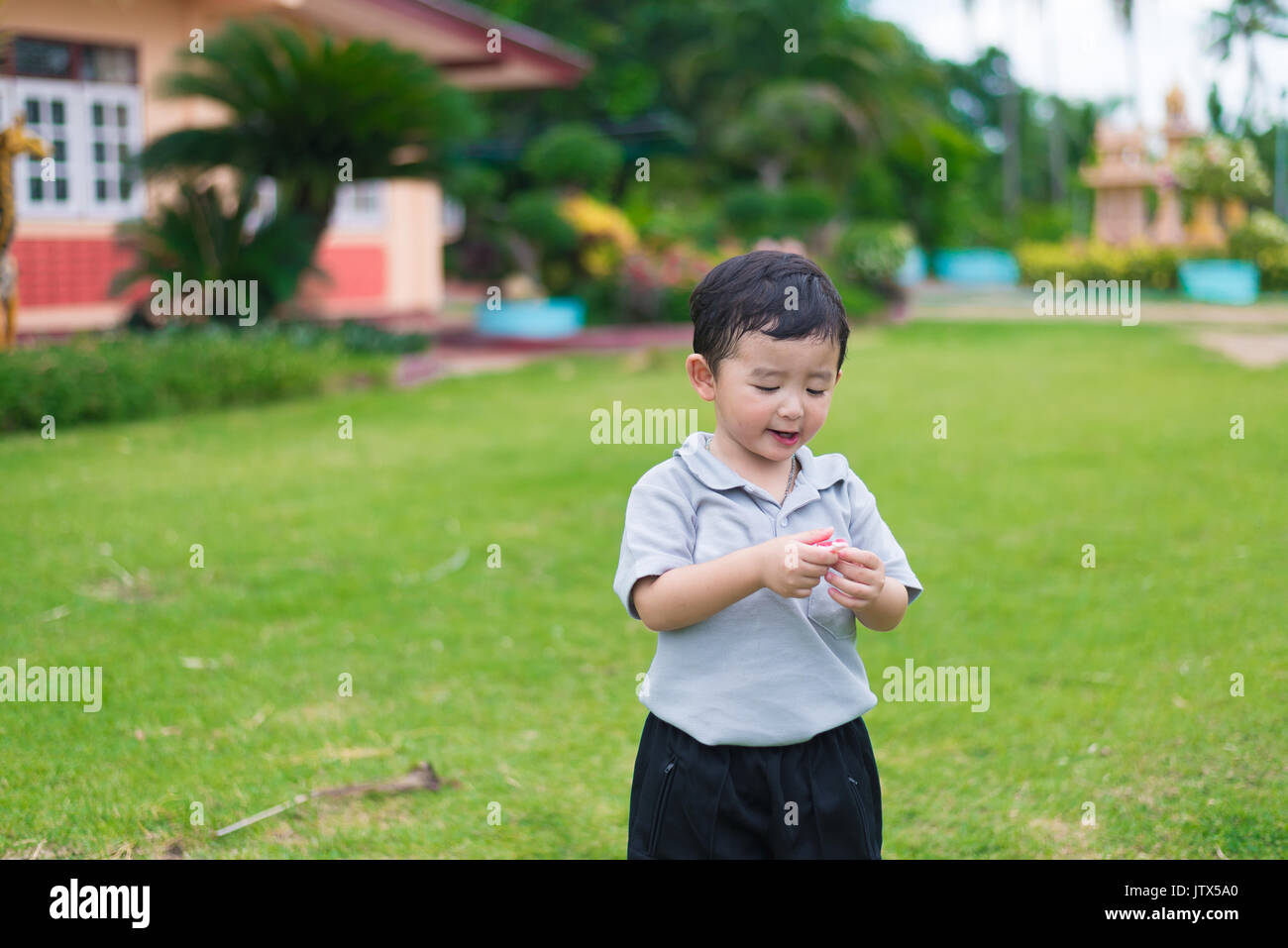 Little Asian kid at the playground under the sunlight in summer ...