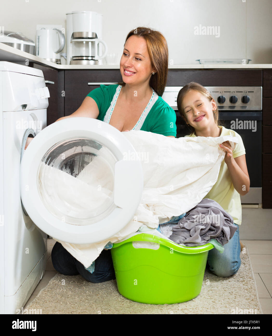 Home laundry. Happy woman with cheerful daughter using washing machine ...