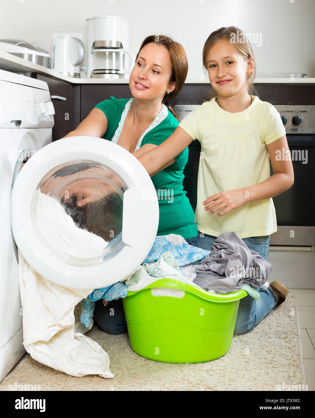 Home laundry. Happy smiling woman with playful daughter using washing ...