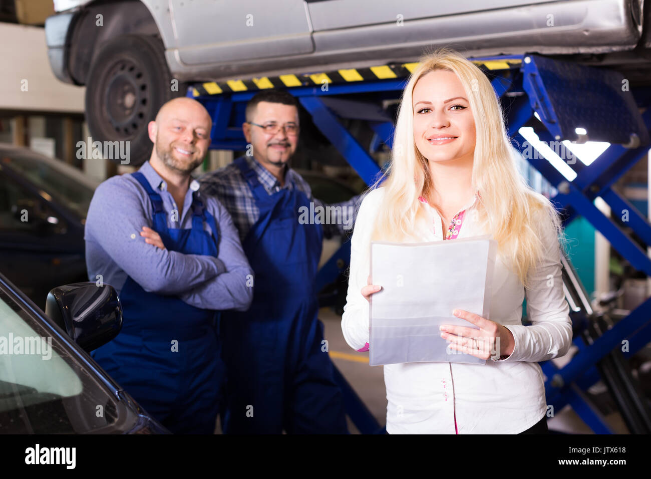 Smiling attractive female insurance agent discussing with mechanics ...