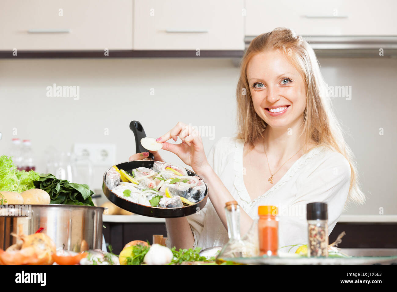 Smiling girl cooking fish in frying pan at kitchen Stock Photo - Alamy