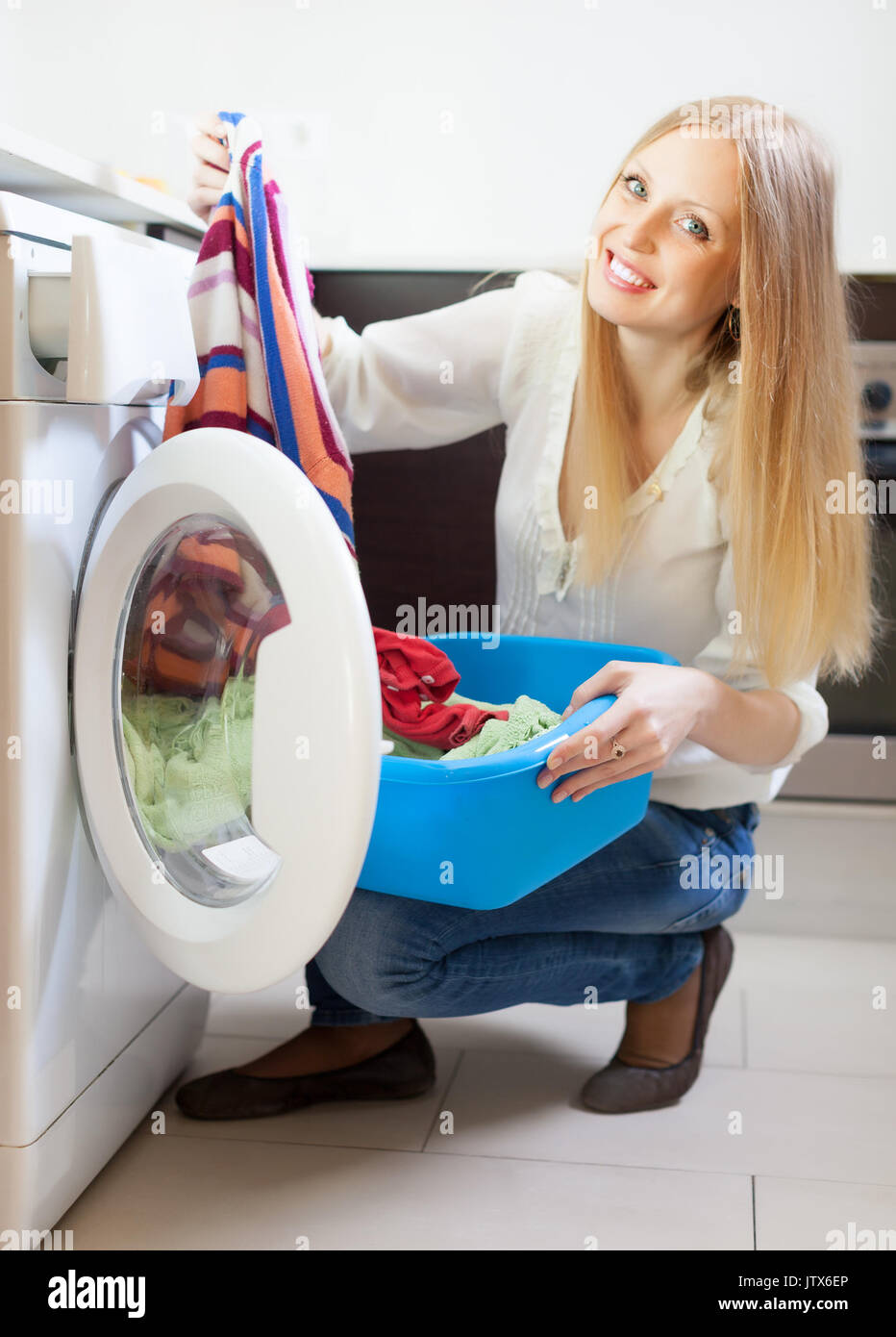 Home laundry. Blonde woman loading the washing machine Stock Photo - Alamy