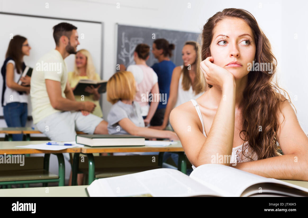 Dejected lonely student with sad expression sits at her desk in the ...