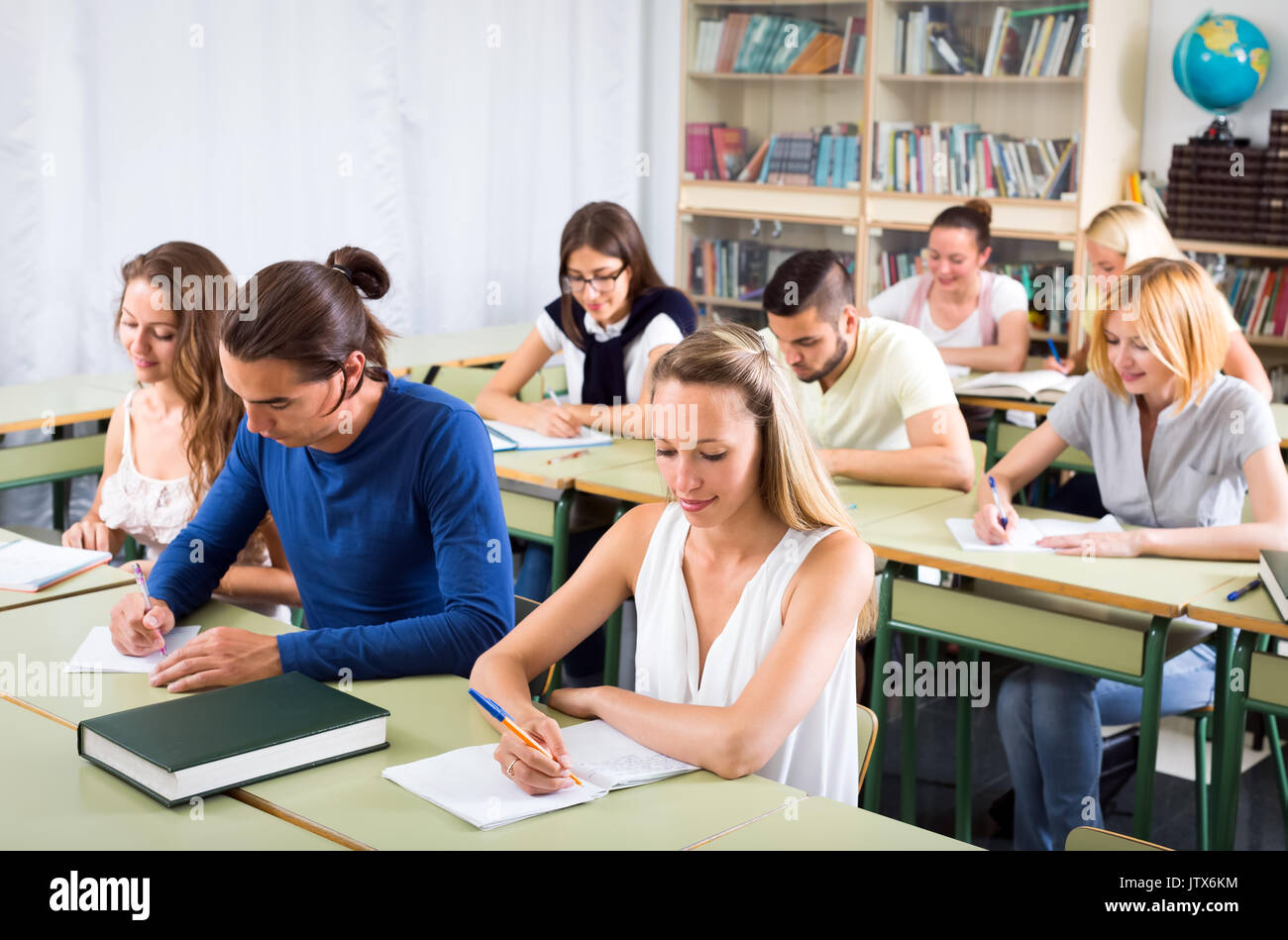 Diligent students writing notes in their copybooks in classroom during ...
