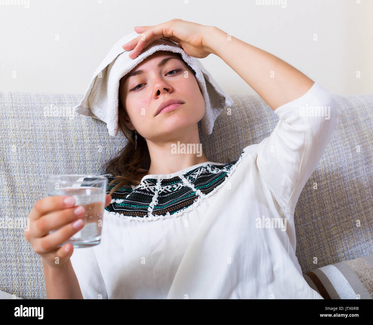 Tired young girl with cold application and headache at home Stock Photo ...