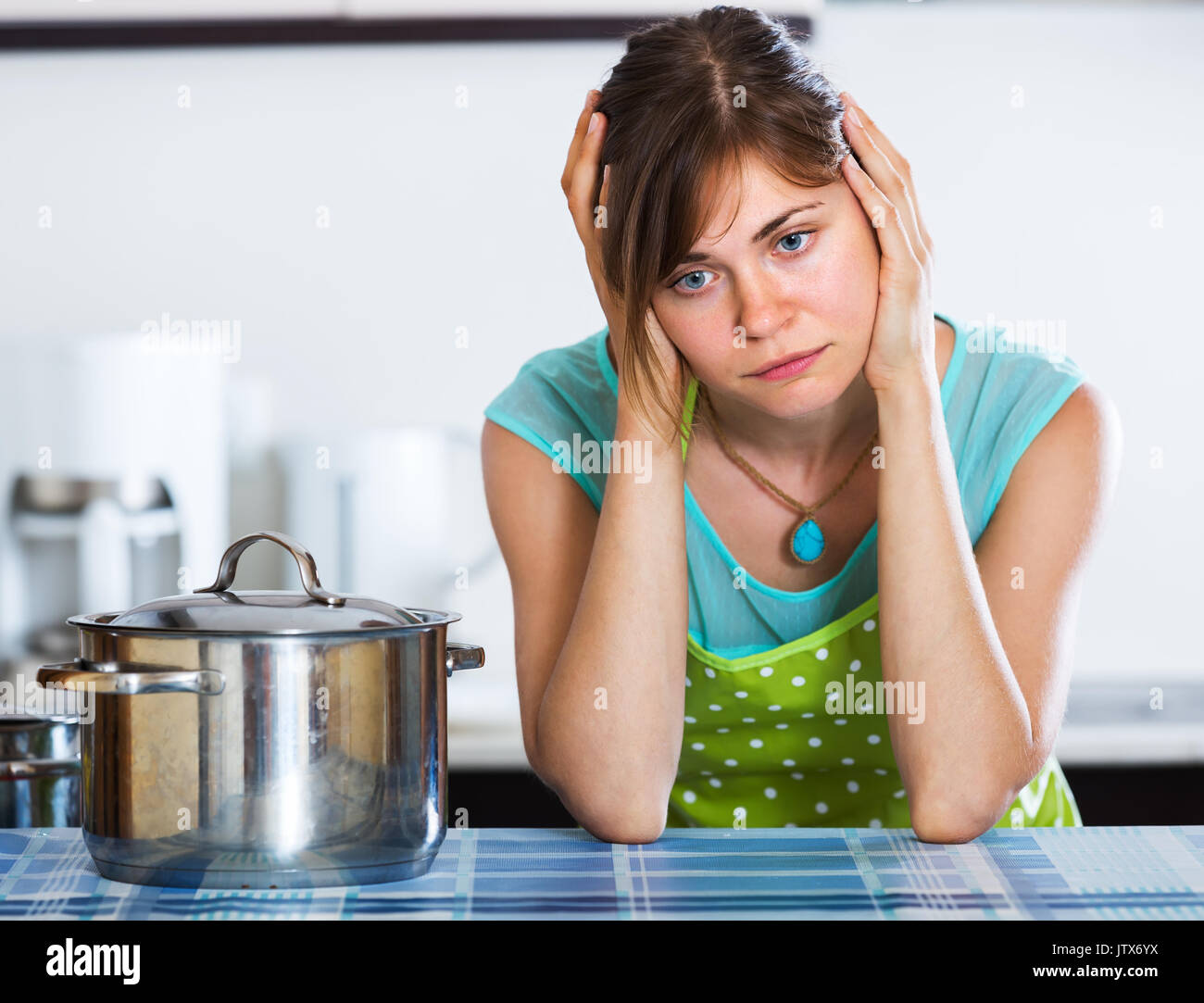 Young woman with sad face cooking dinner in the kitchen Stock Photo - Alamy