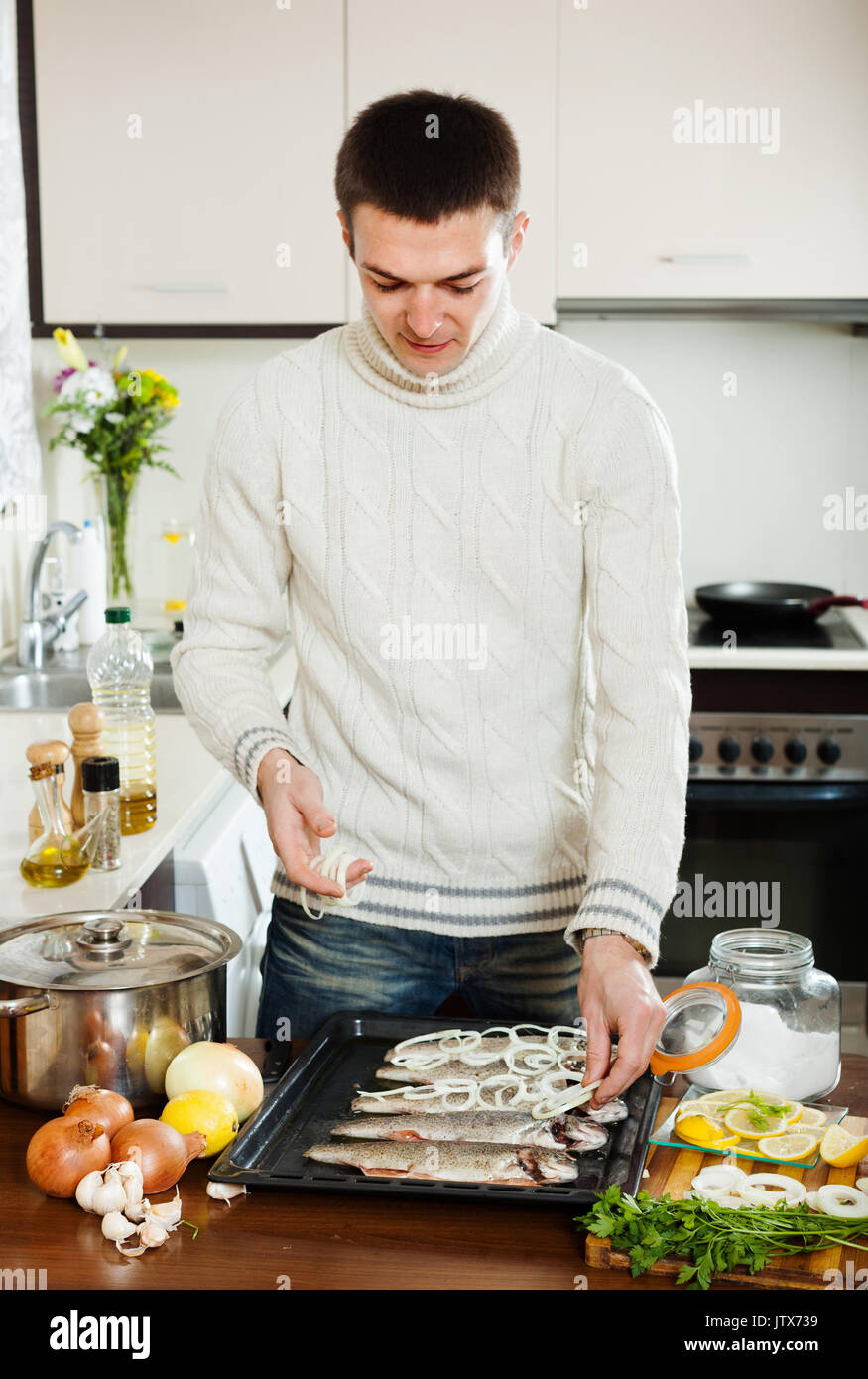 guy cooking fish with onion in baking sheet at home kitchen Stock Photo ...