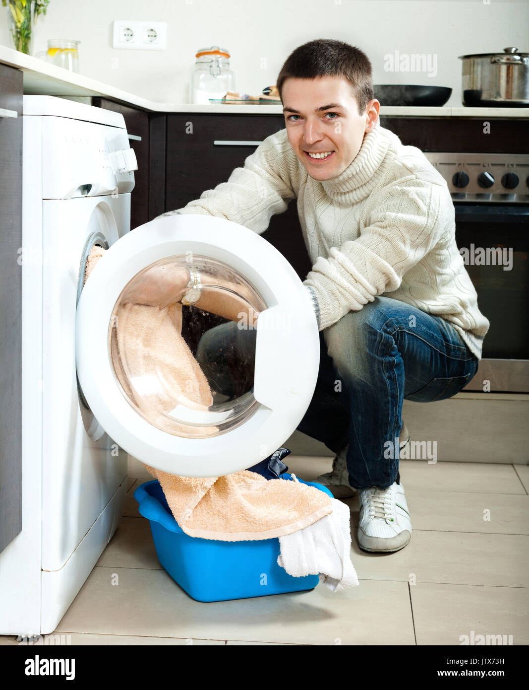 Smiling man looking clothes near washing machine Stock Photo - Alamy