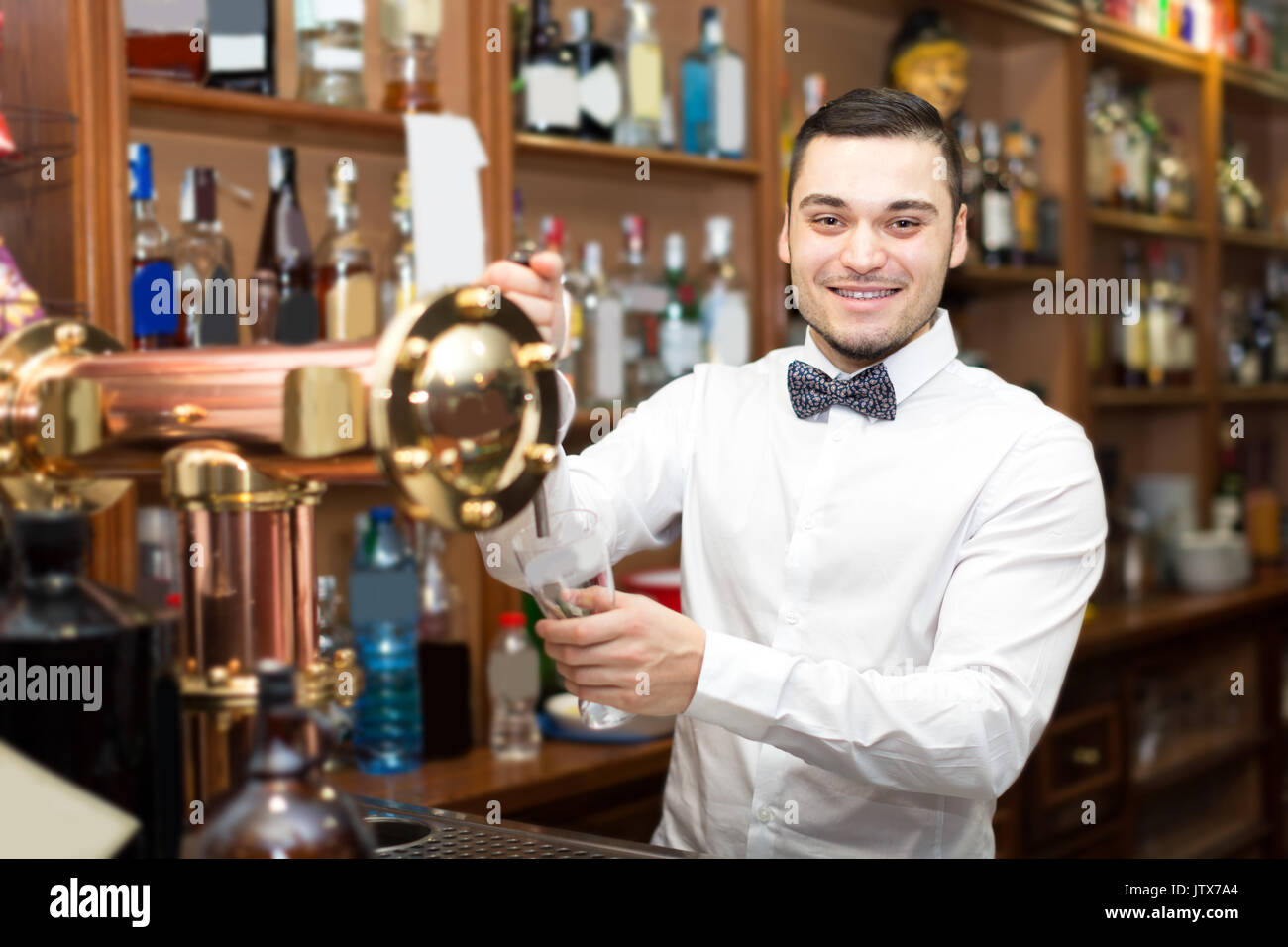 Happy young barman pouring beverages and smiling Stock Photo - Alamy