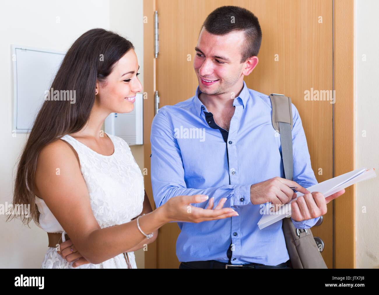 Happy russian woman and man standing with official papers near door ...
