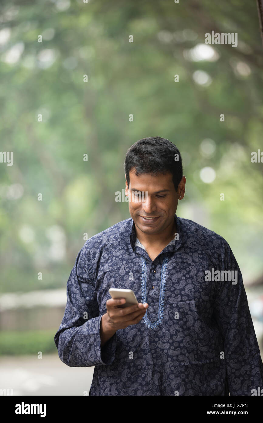 Happy Indian man using a smart phone on street. Traditional indian male ...