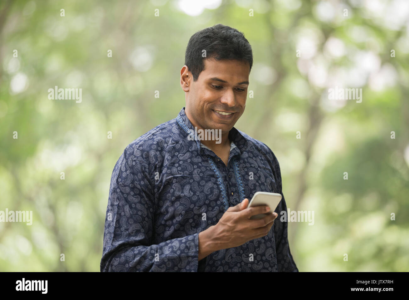 Happy Indian man using a smart phone on street. Traditional indian male ...
