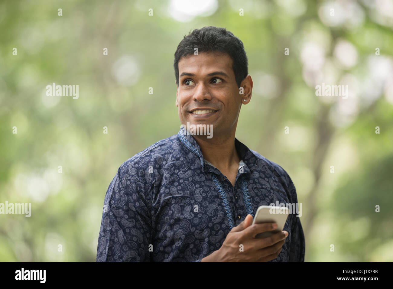 Happy Indian man using a smart phone on street. Traditional indian male ...
