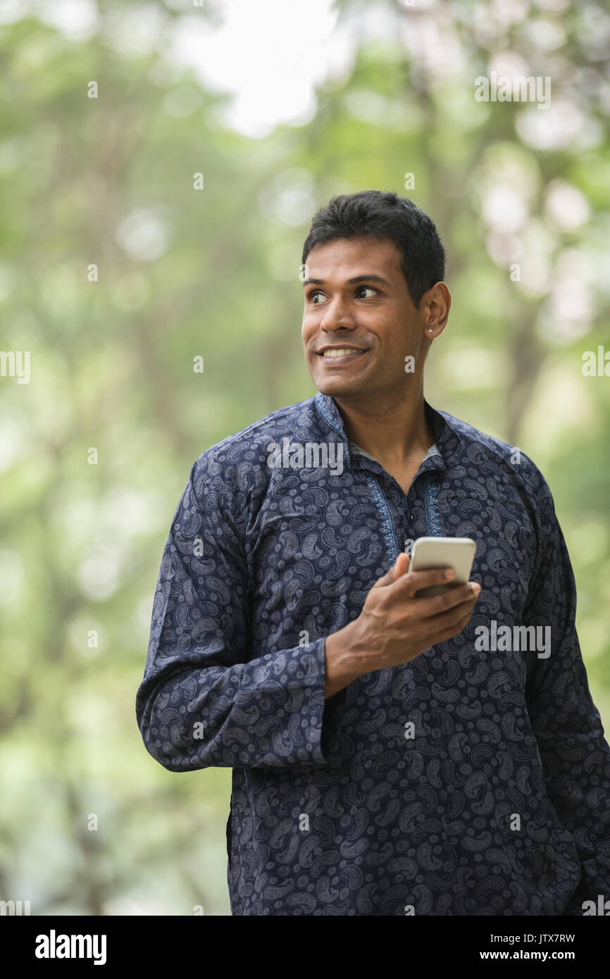 Happy Indian man using a smart phone on street. Traditional indian male ...