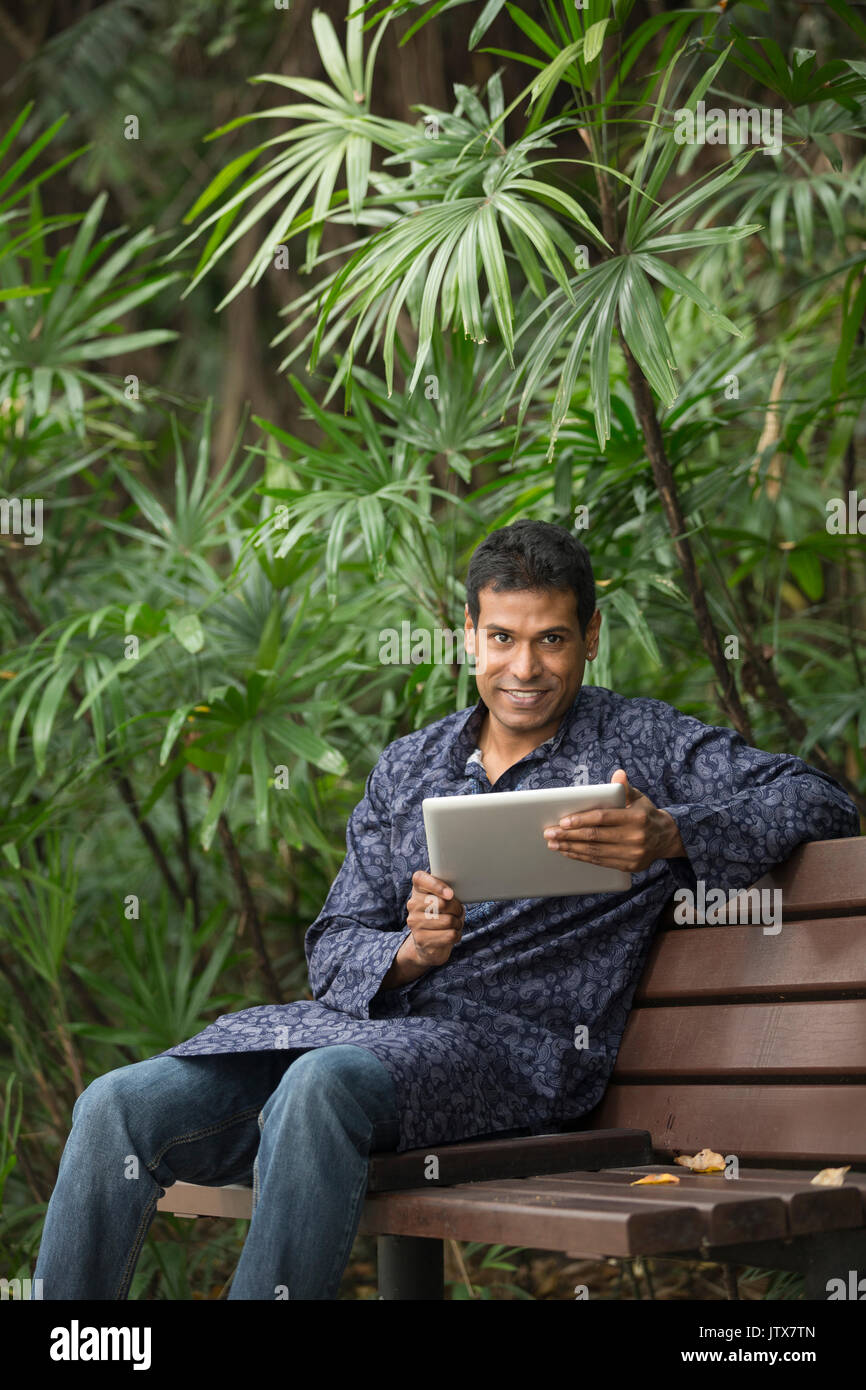 Happy Indian man using tablet computer on street. Traditional indian ...