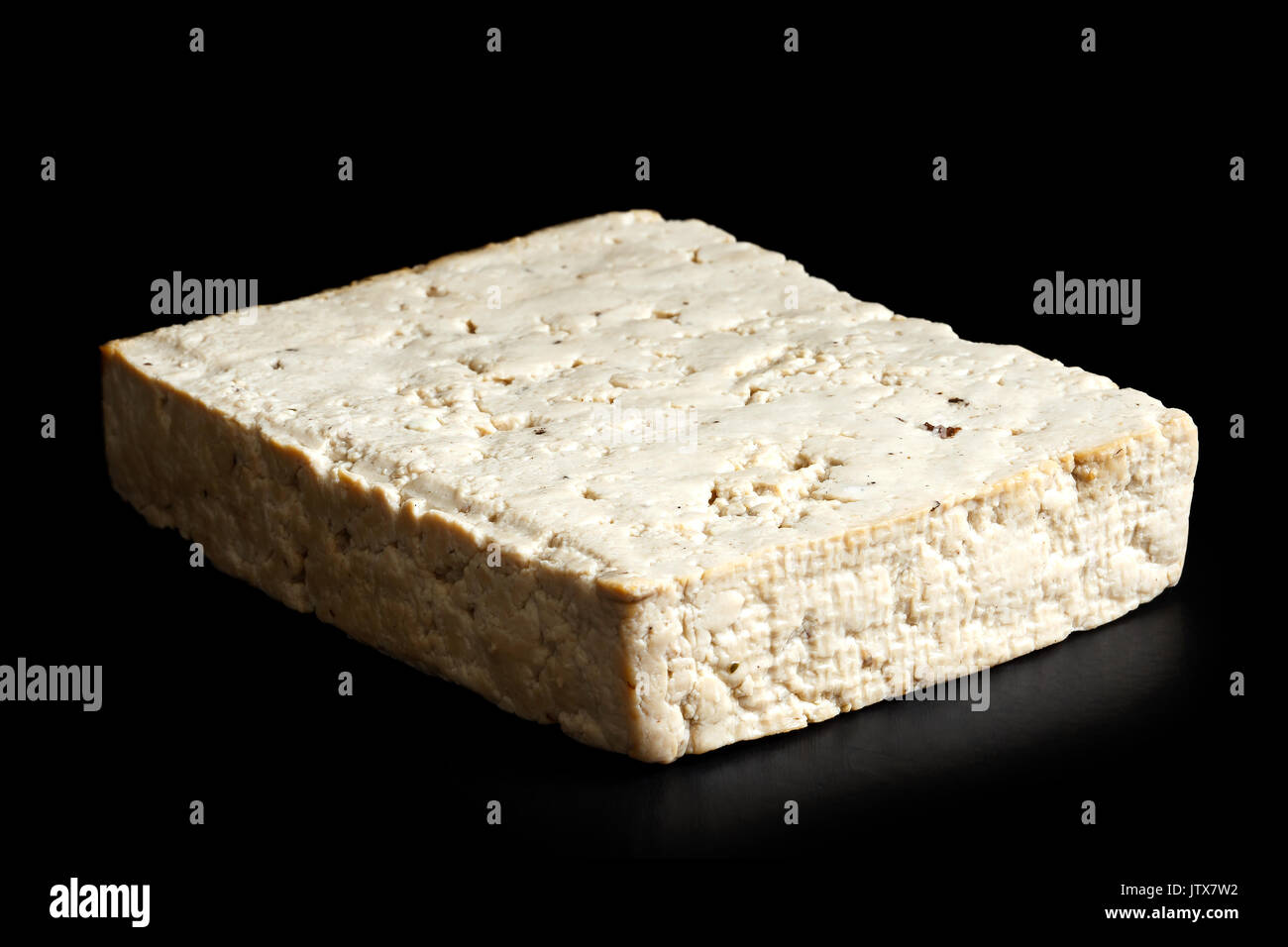 Single block of lightly smoked tofu isolated on black Stock Photo - Alamy