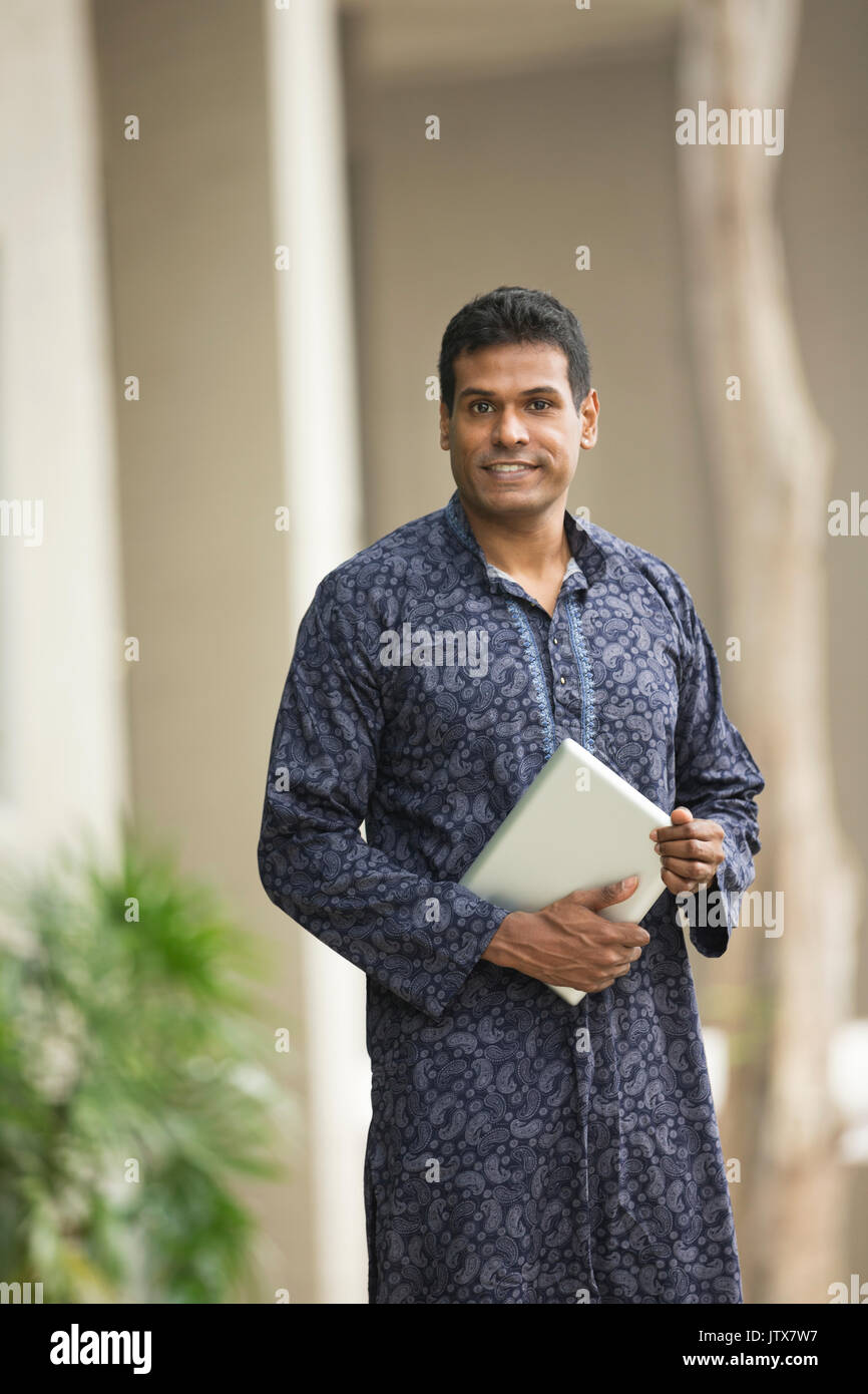 Happy Indian man using tablet computer on street. Traditional indian ...