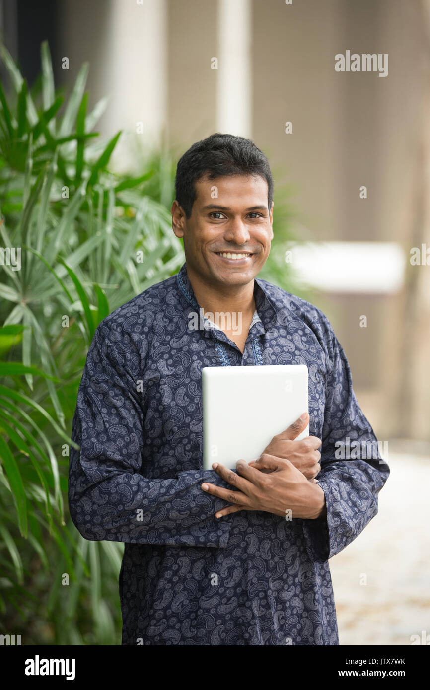 Happy Indian man using tablet computer on street. Traditional indian ...