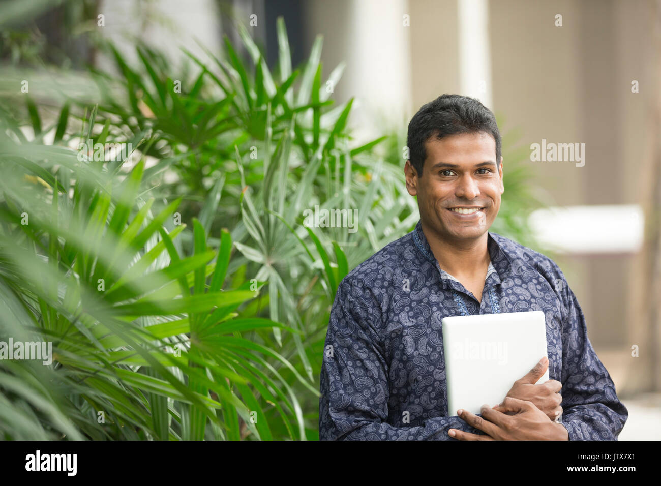Happy Indian man using tablet computer on street. Traditional indian ...