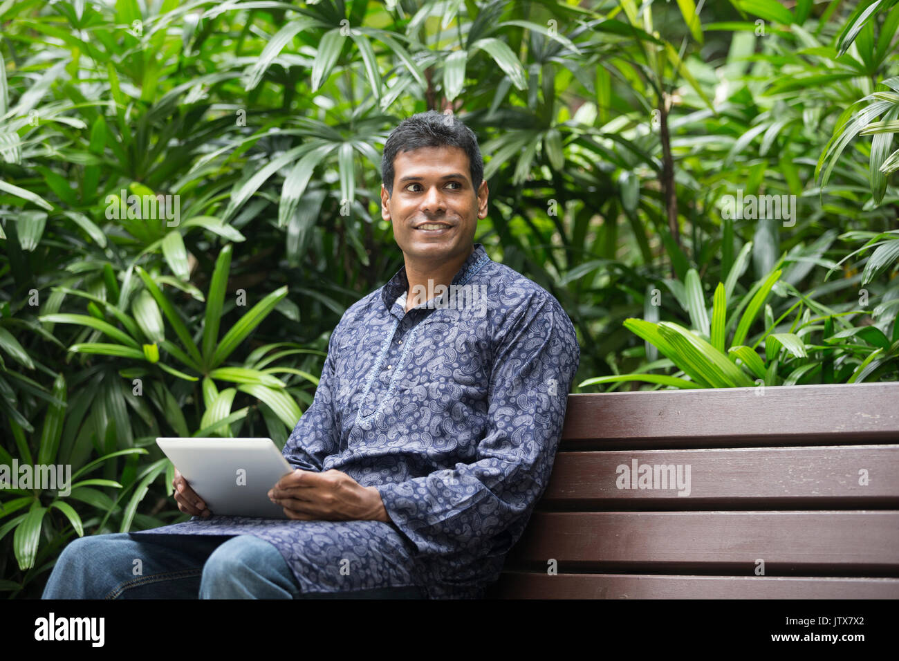 Happy Indian man using tablet computer on street. Traditional indian ...