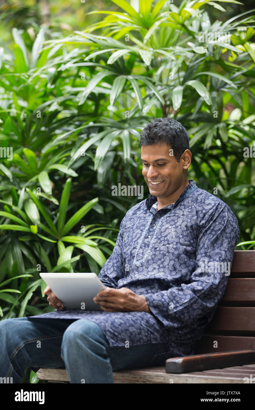 Happy Indian man using tablet computer on street. Traditional indian ...