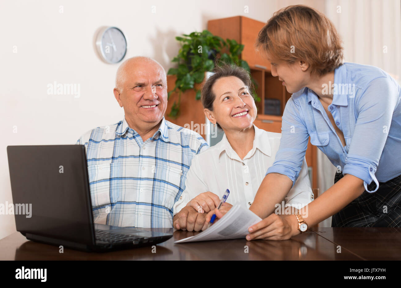 Mature couple answer questions of outreach worker with laptop in office ...