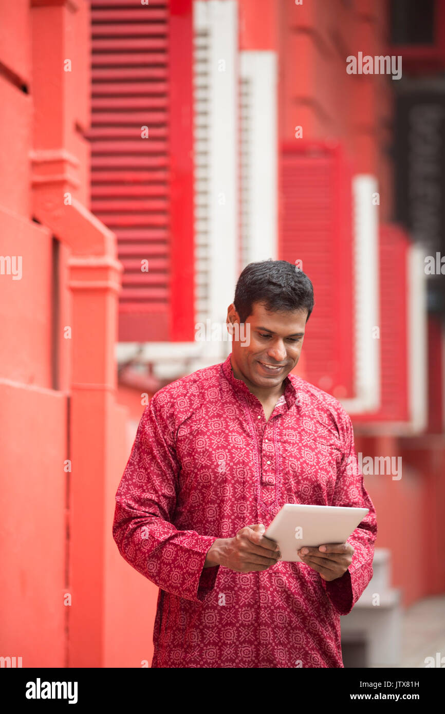 Happy Indian man using tablet computer on street. Traditional indian ...