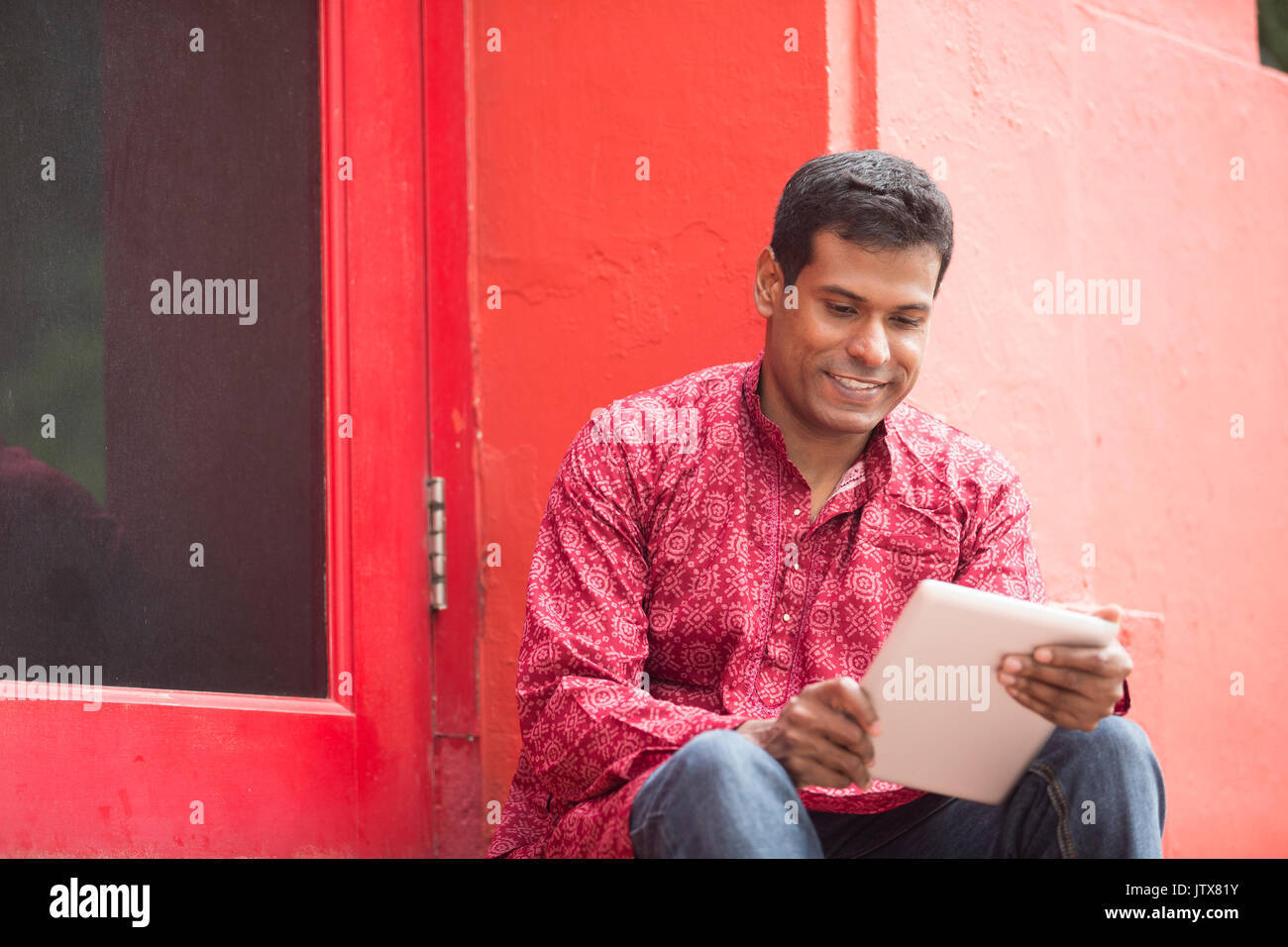 Happy Indian man using tablet computer on street. Traditional indian ...