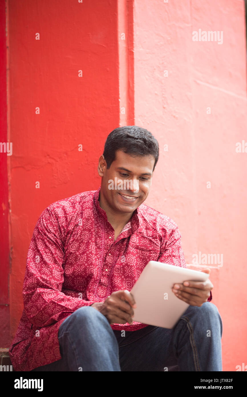 Happy Indian man using tablet computer on street. Traditional indian ...