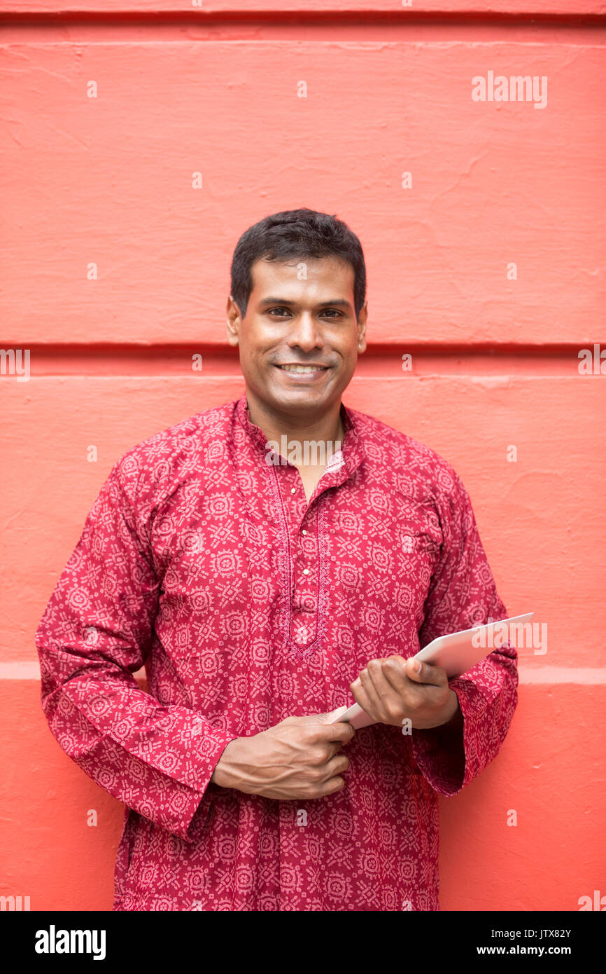 Happy Indian man using tablet computer on street. Traditional indian ...