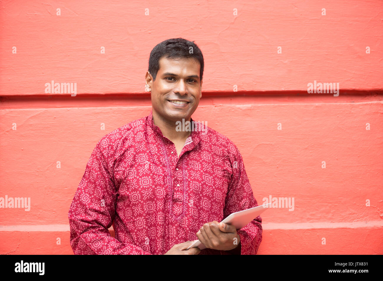 Happy Indian man using tablet computer on street. Traditional indian ...