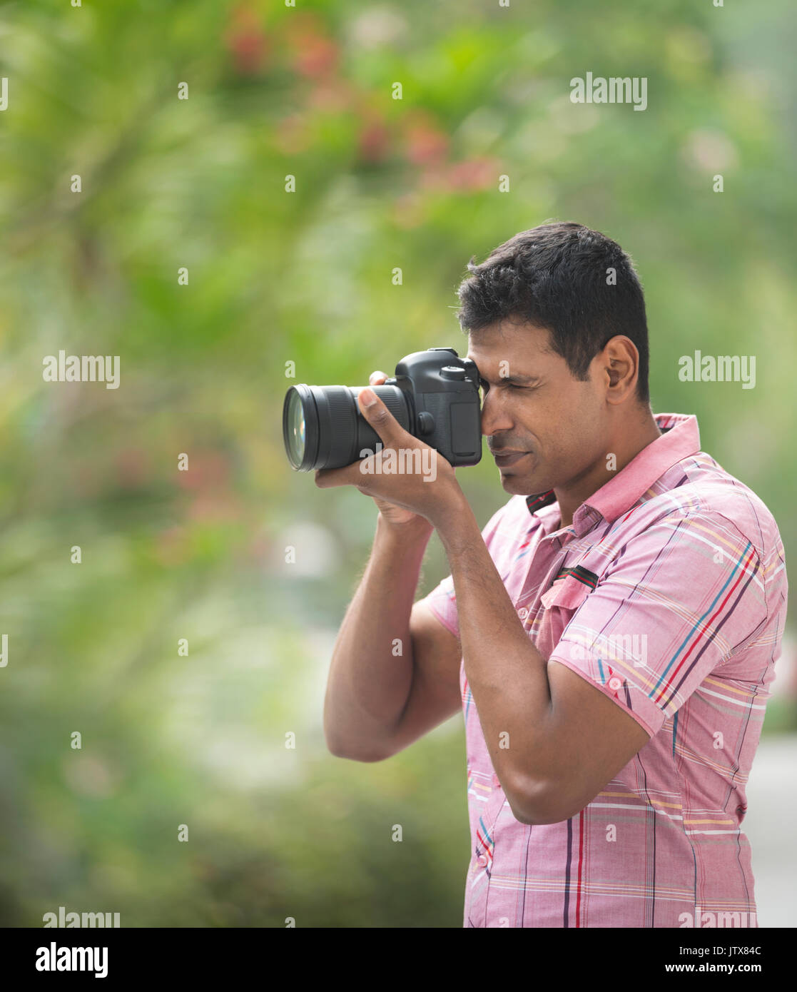 Portrait of happy Indian man taking photos with a camera in the city ...