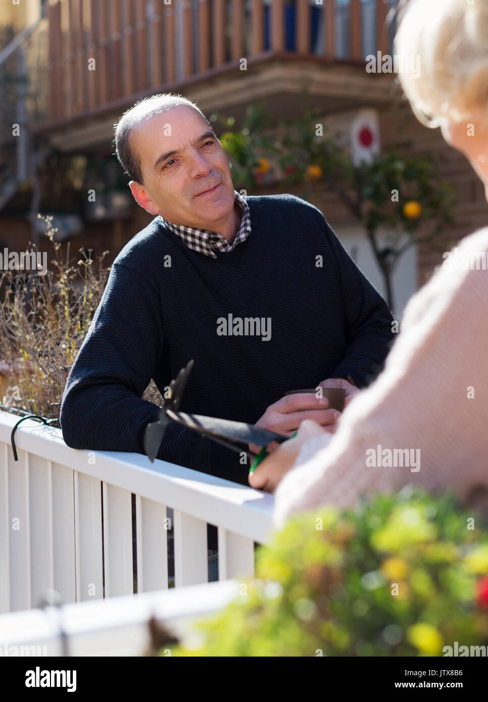 Mature woman talking with smiling male neighbor at balcon Stock Photo ...
