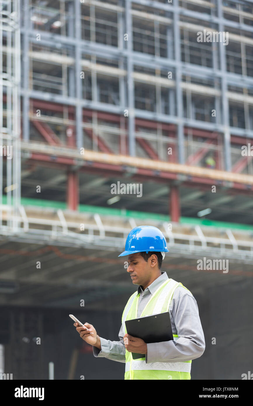 Portrait of a male Indian builder or industrial engineer at work using ...