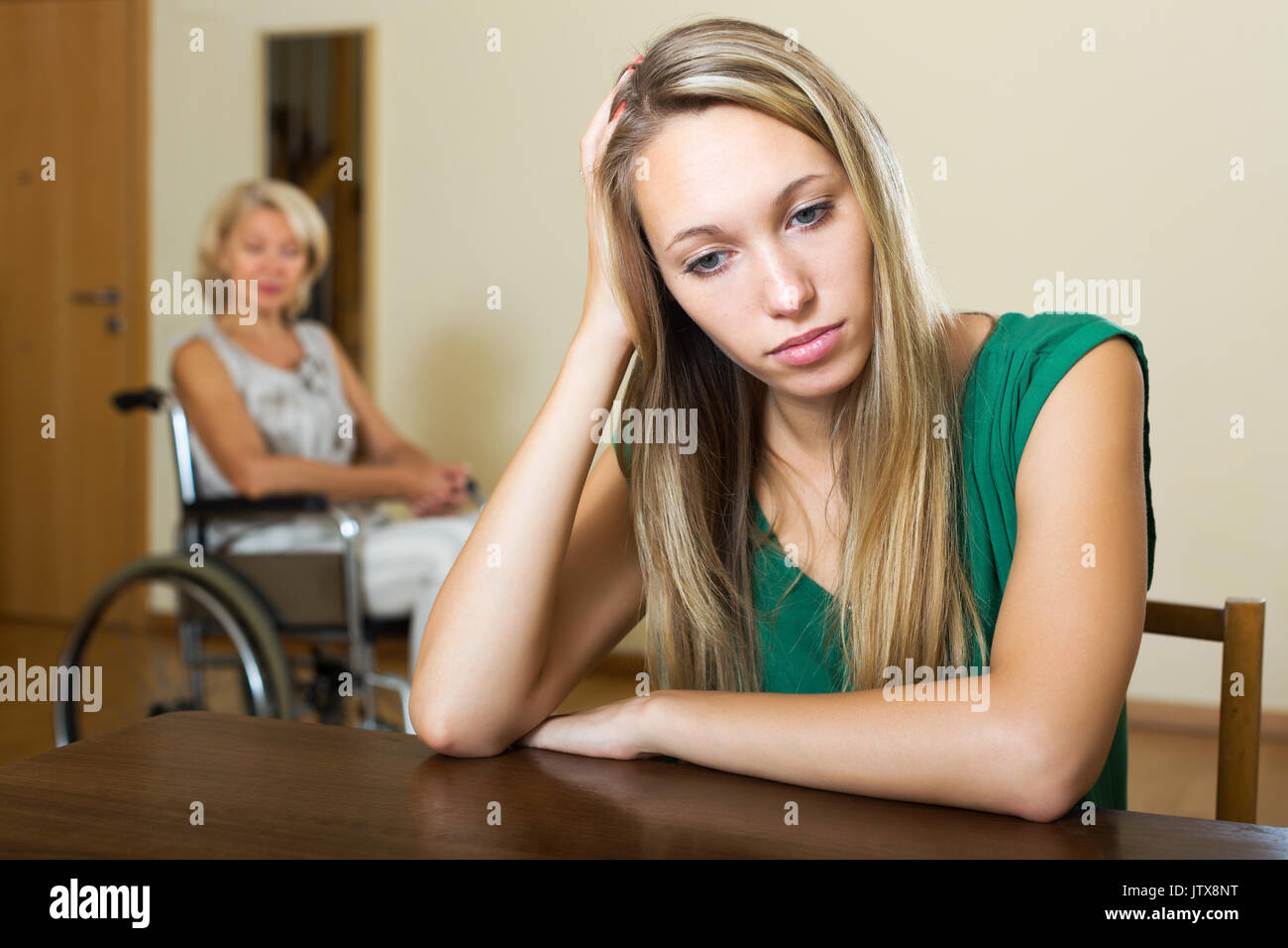 Tired girl and disabled person on chair indoor Stock Photo - Alamy