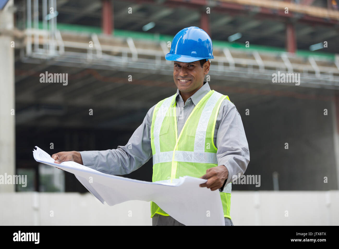 Indian construction manager or Architect checking the blueprint plans ...