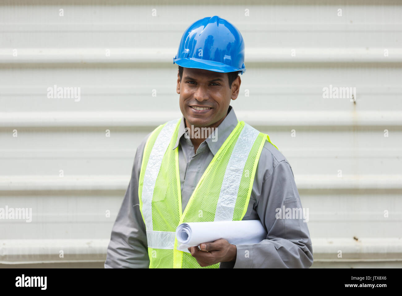 Portrait of a male Indian industrial engineer at work looking at ...