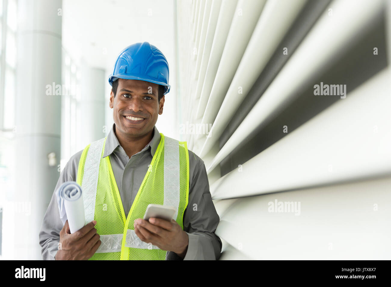Portrait of a male Indian industrial engineer at work looking at ...