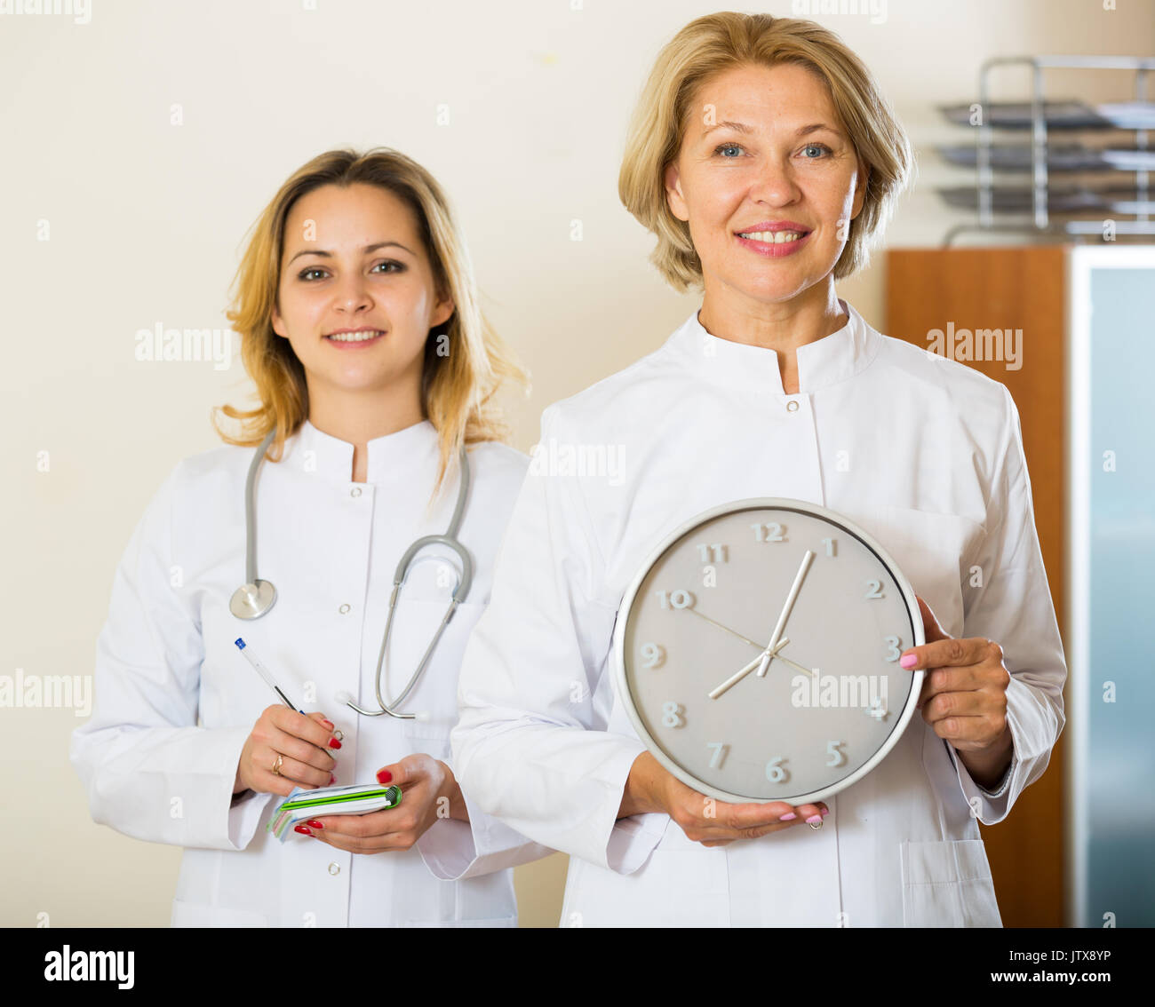 Time for appointment: mature and young doctors with clock Stock Photo ...