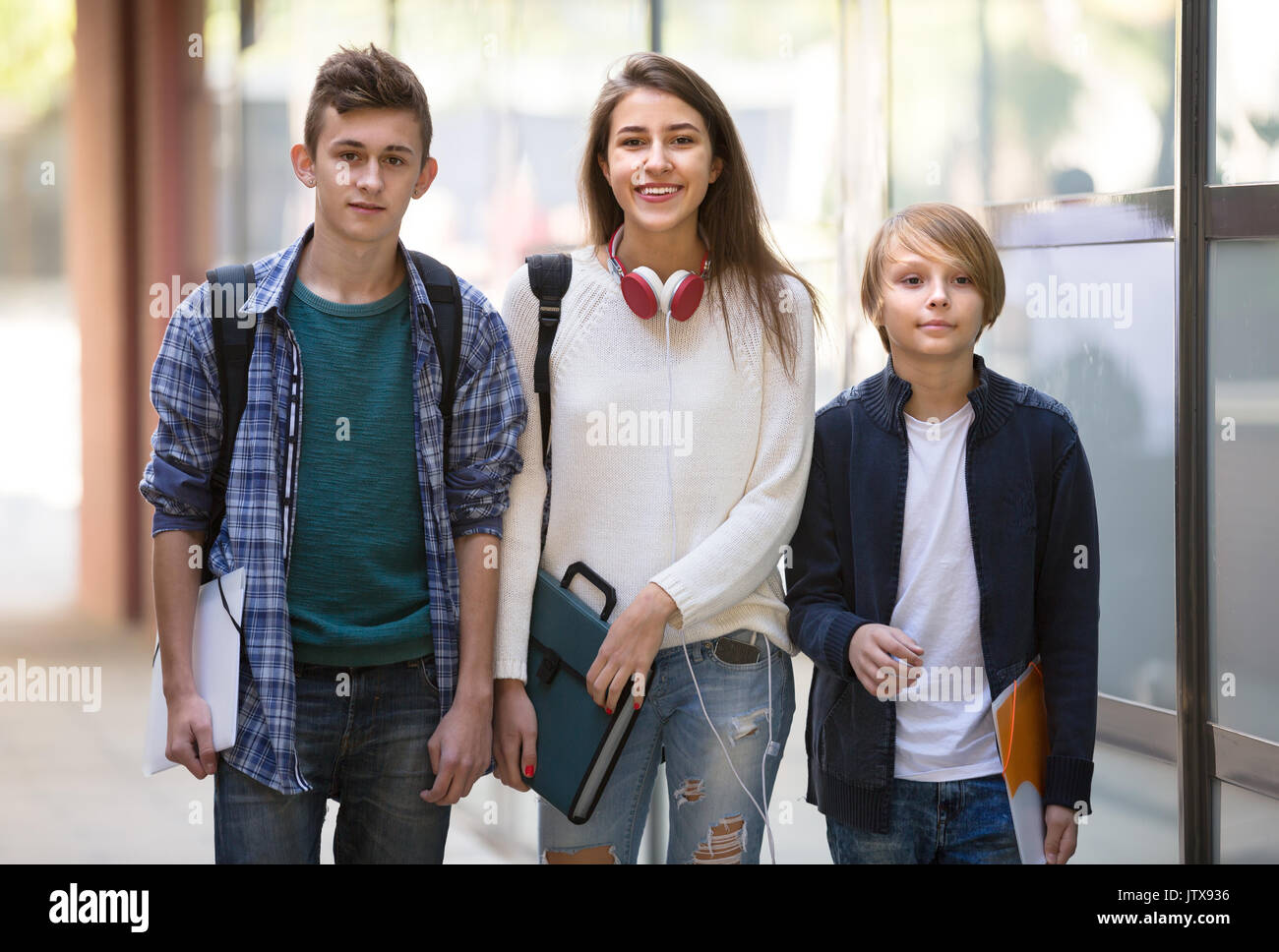Three ordinary teenage students going to college through city street ...