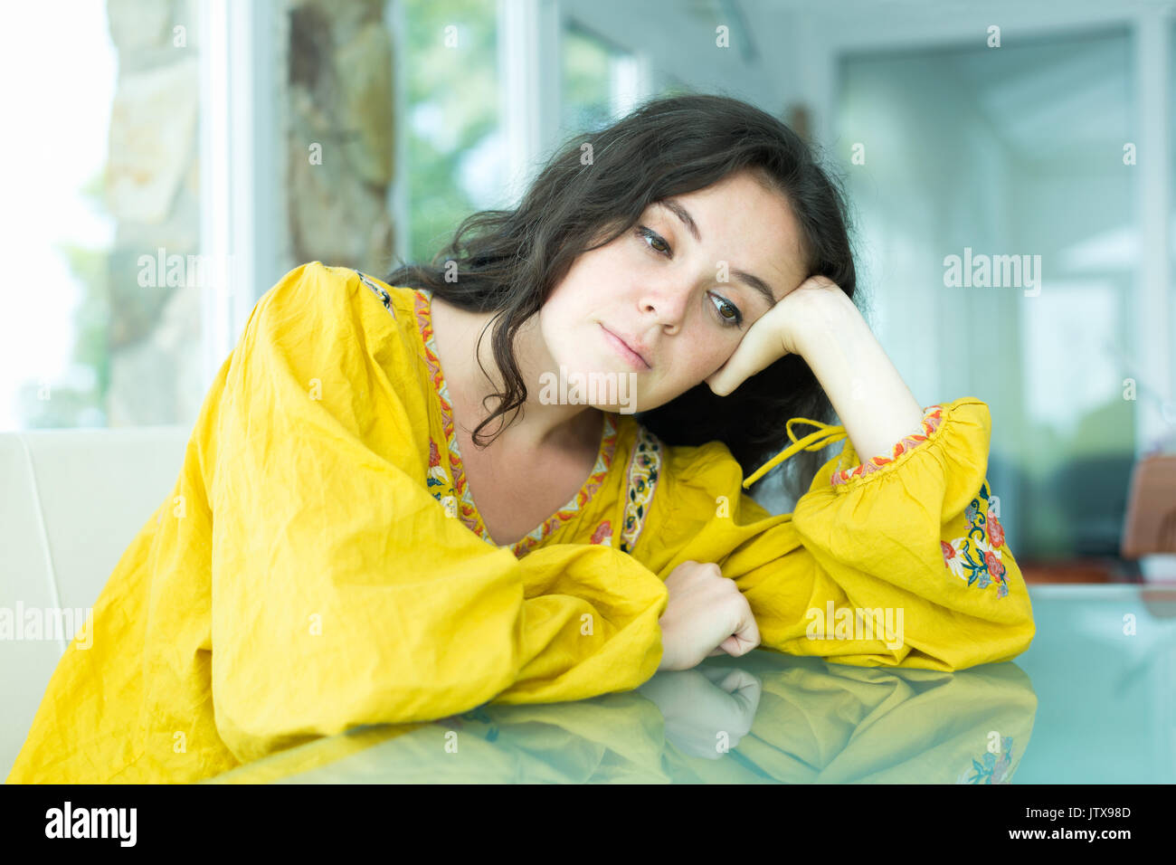 Sad girl sitting along at the table at home Stock Photo - Alamy