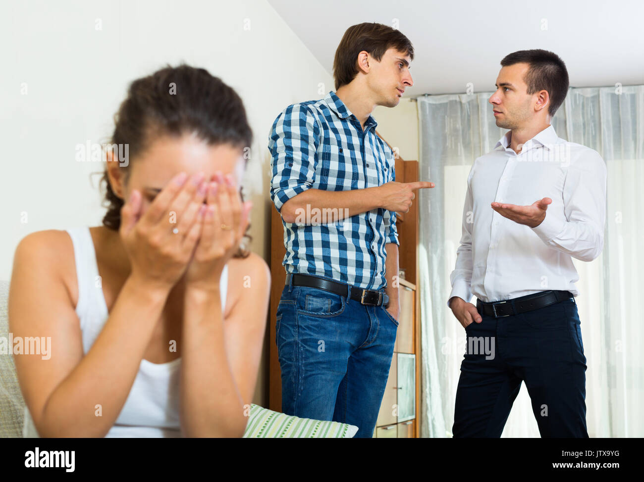Sad european girl having argue with her friends at home. focus on men ...