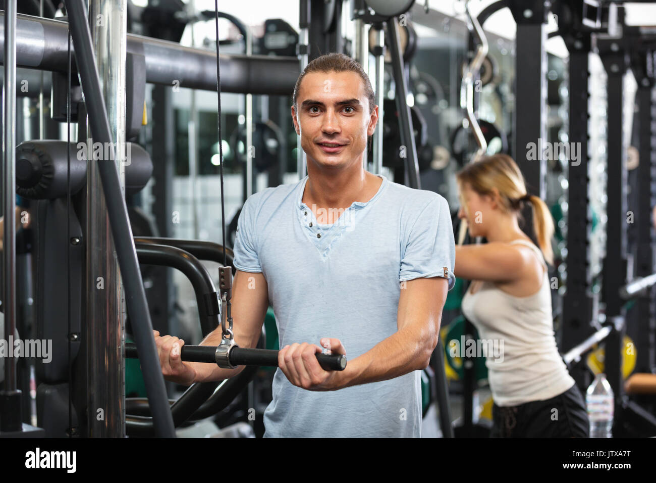 Smiling young people having weightlifting training in health club Stock ...