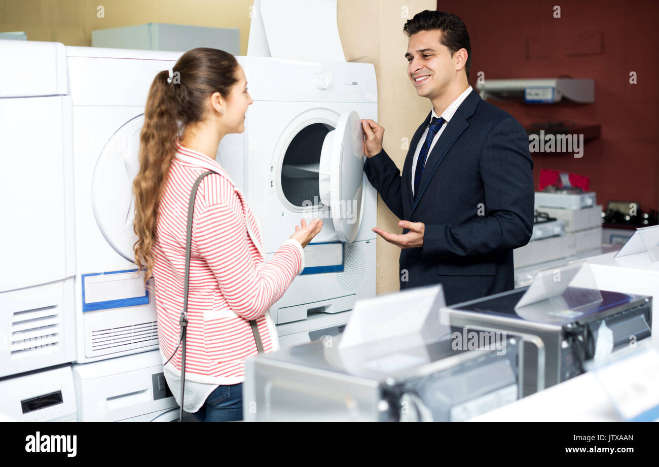Happy family couple buying new clothes washer in supermarket. Focus on ...